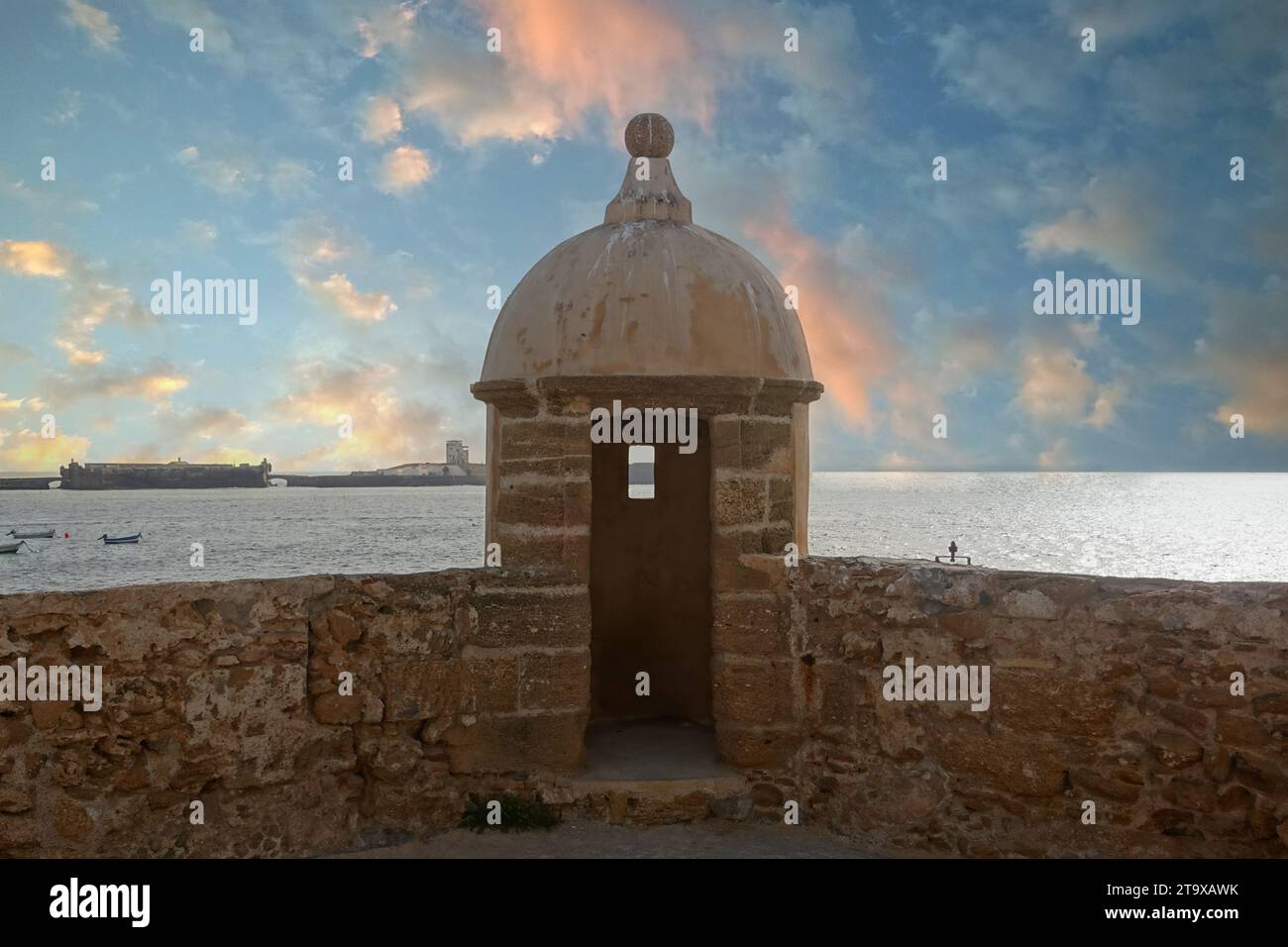 Sunset reflects in the clouds over Cadiz Bay from inside the Castillo ...