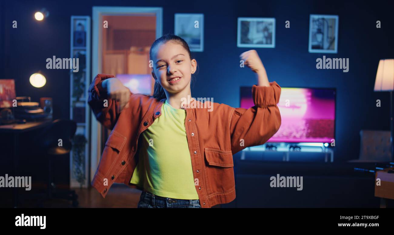 Happy child in apartment illuminated by RBG lights filming dance ...