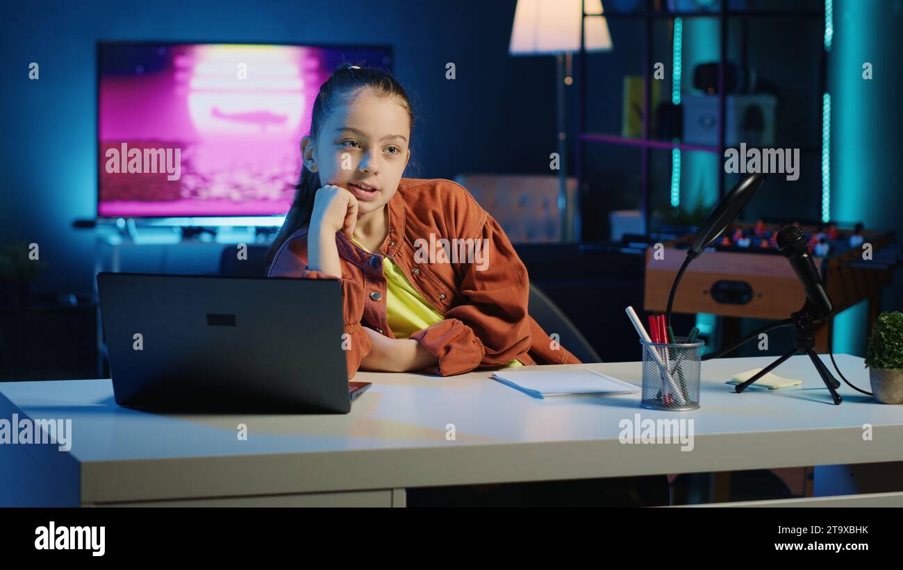 Young kid filming family vlog in home studio, talking about boring day at school for her ...