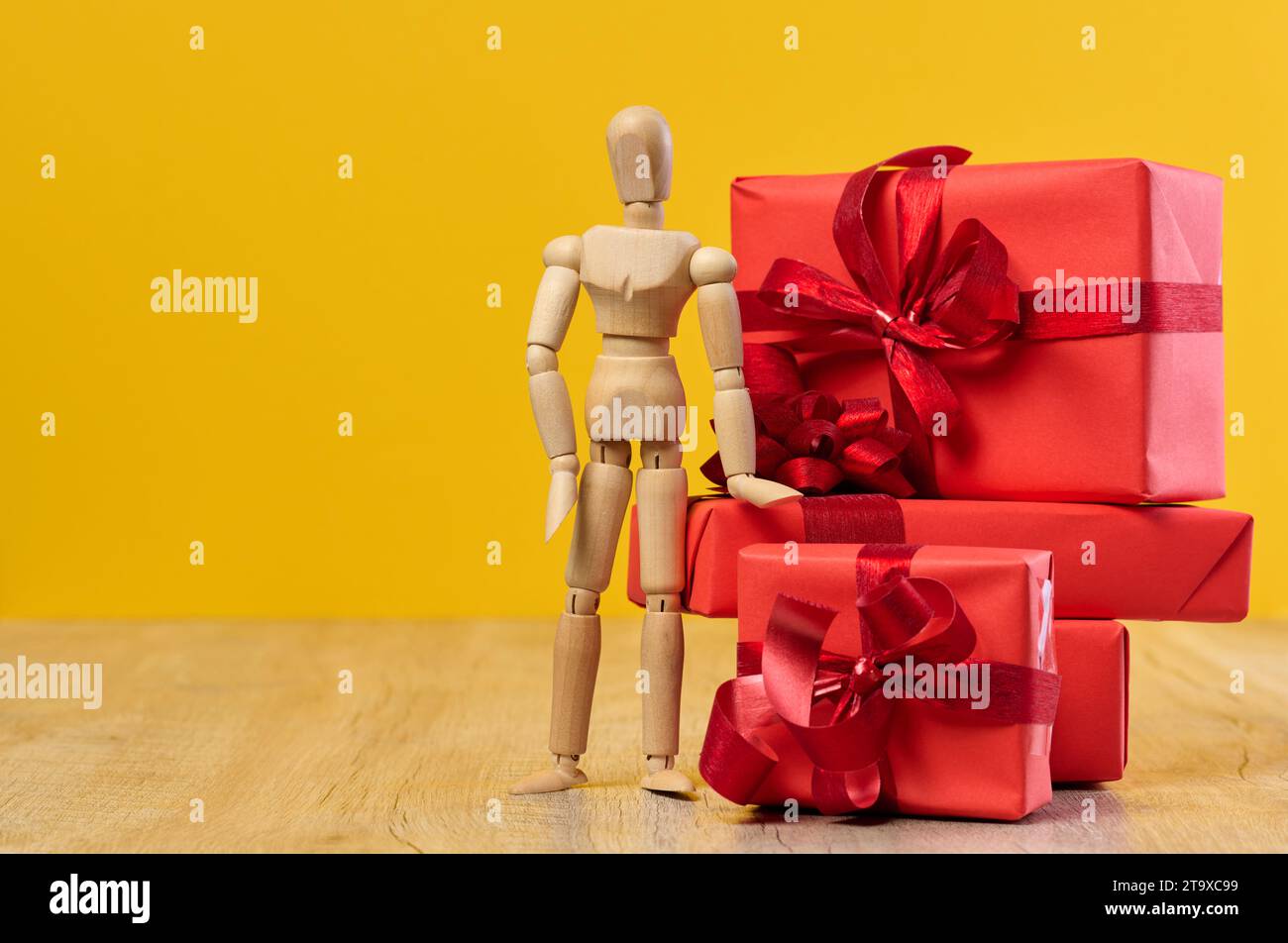 Stack of gifts and wooden mannequin on yellow background, holiday Stock ...