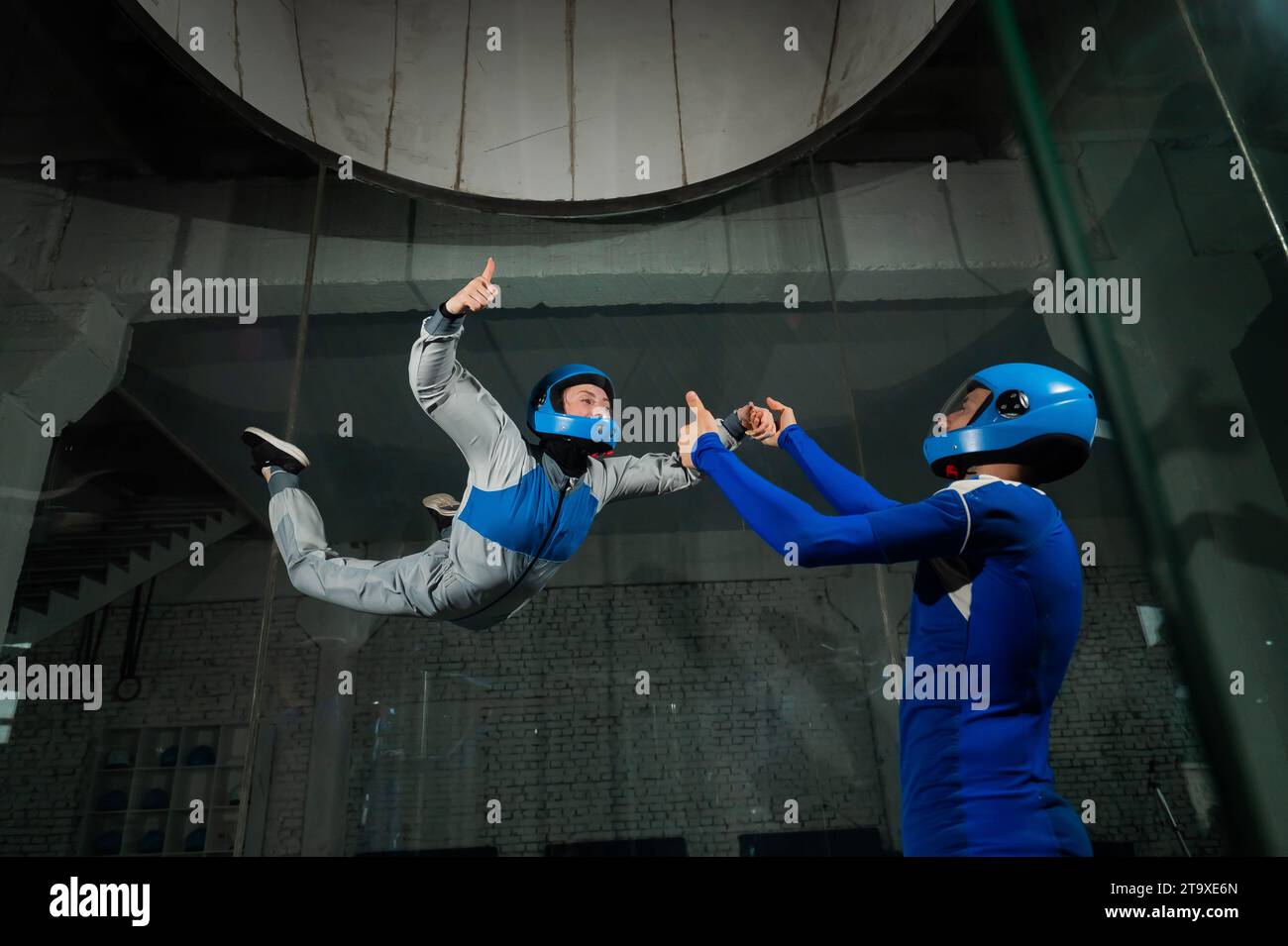 A male instructor teaches a woman how to fly in a wind tunnel. Free ...