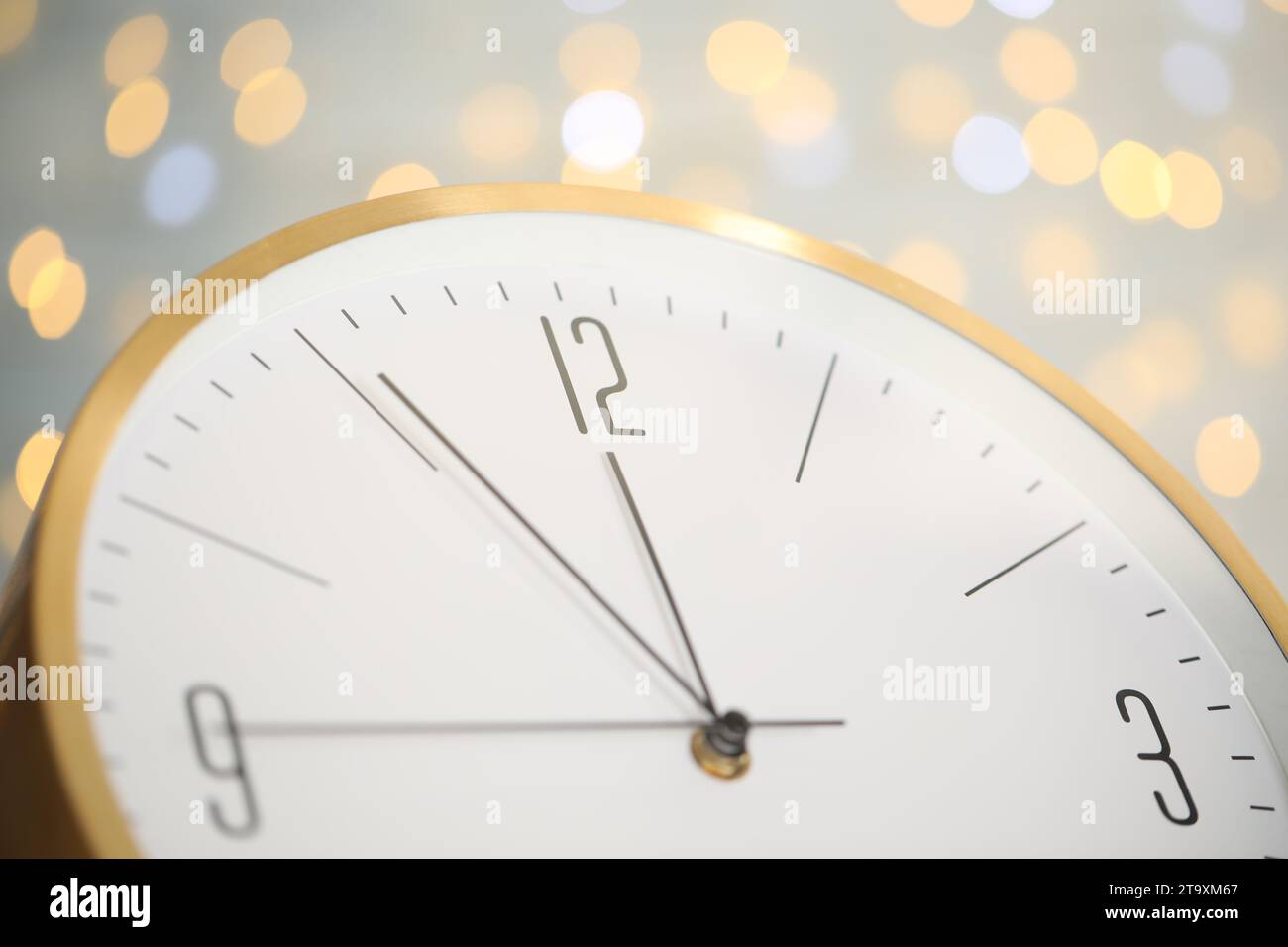 Clock showing five minutes until midnight on blurred background ...
