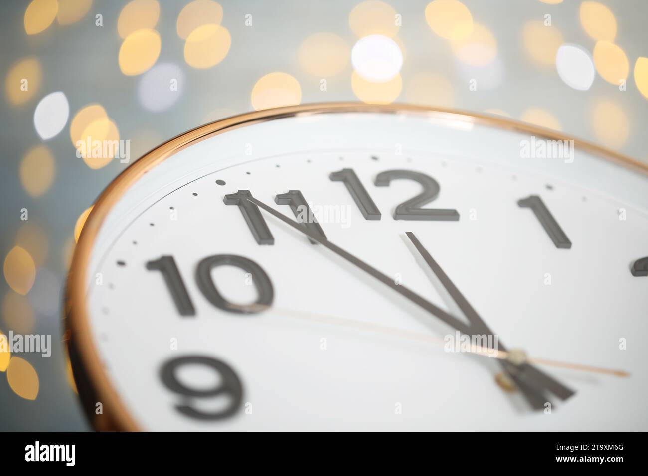 Clock showing five minutes until midnight on blurred background ...