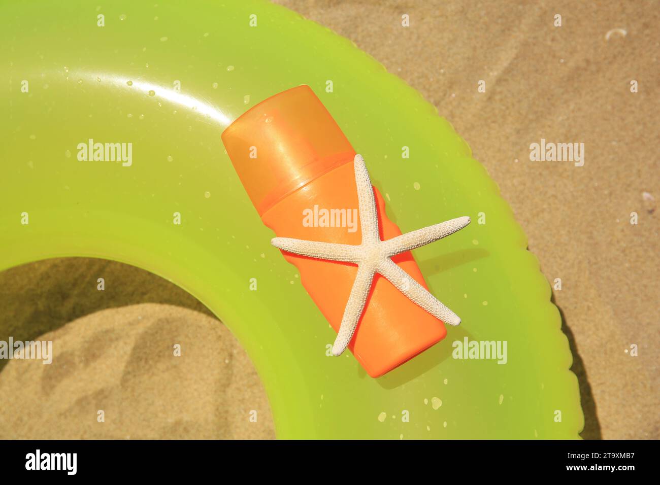 Sunscreen, starfish and inflatable ring on sand, top view. Sun ...