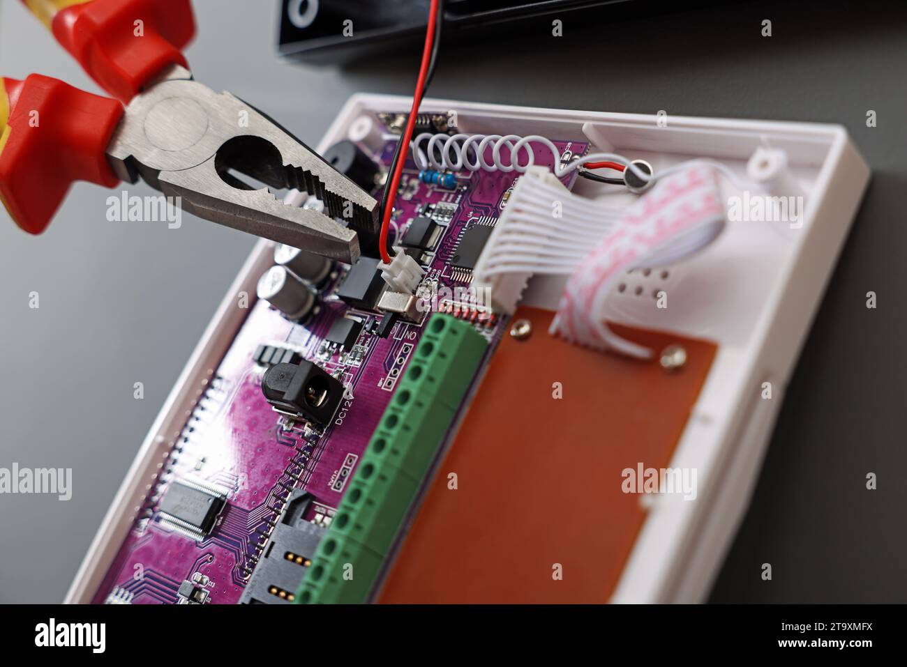 Using pliers while installing alarm system on gray wall, closeup Stock ...
