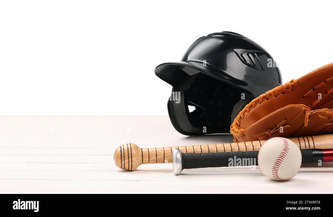 Baseball glove, bats, ball and batting helmet on wooden table against ...