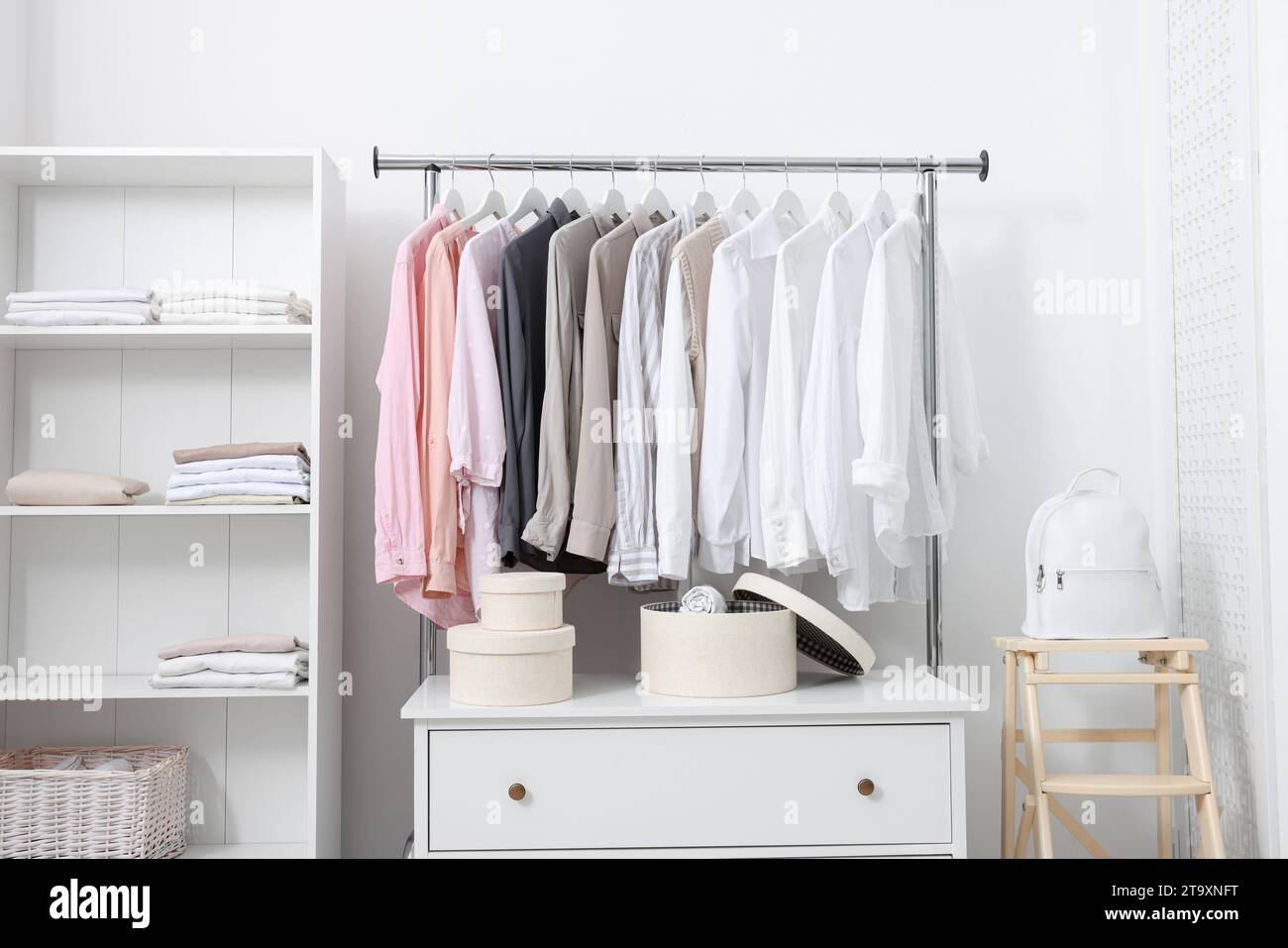Wardrobe organization. Rack with different stylish clothes, chest of ...