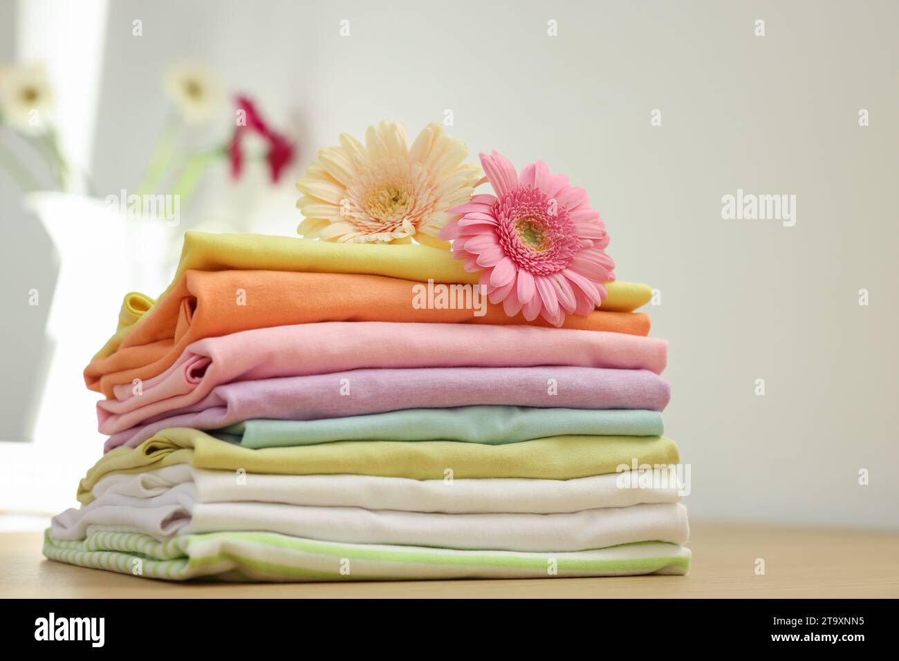 Stack of clean clothes and flowers on table Stock Photo - Alamy