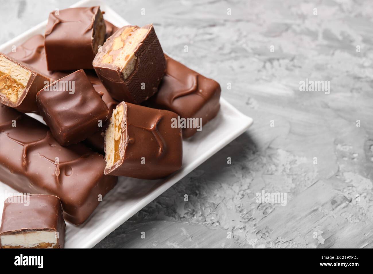 Tasty chocolate bars with nougat, caramel and nuts on gray textured ...