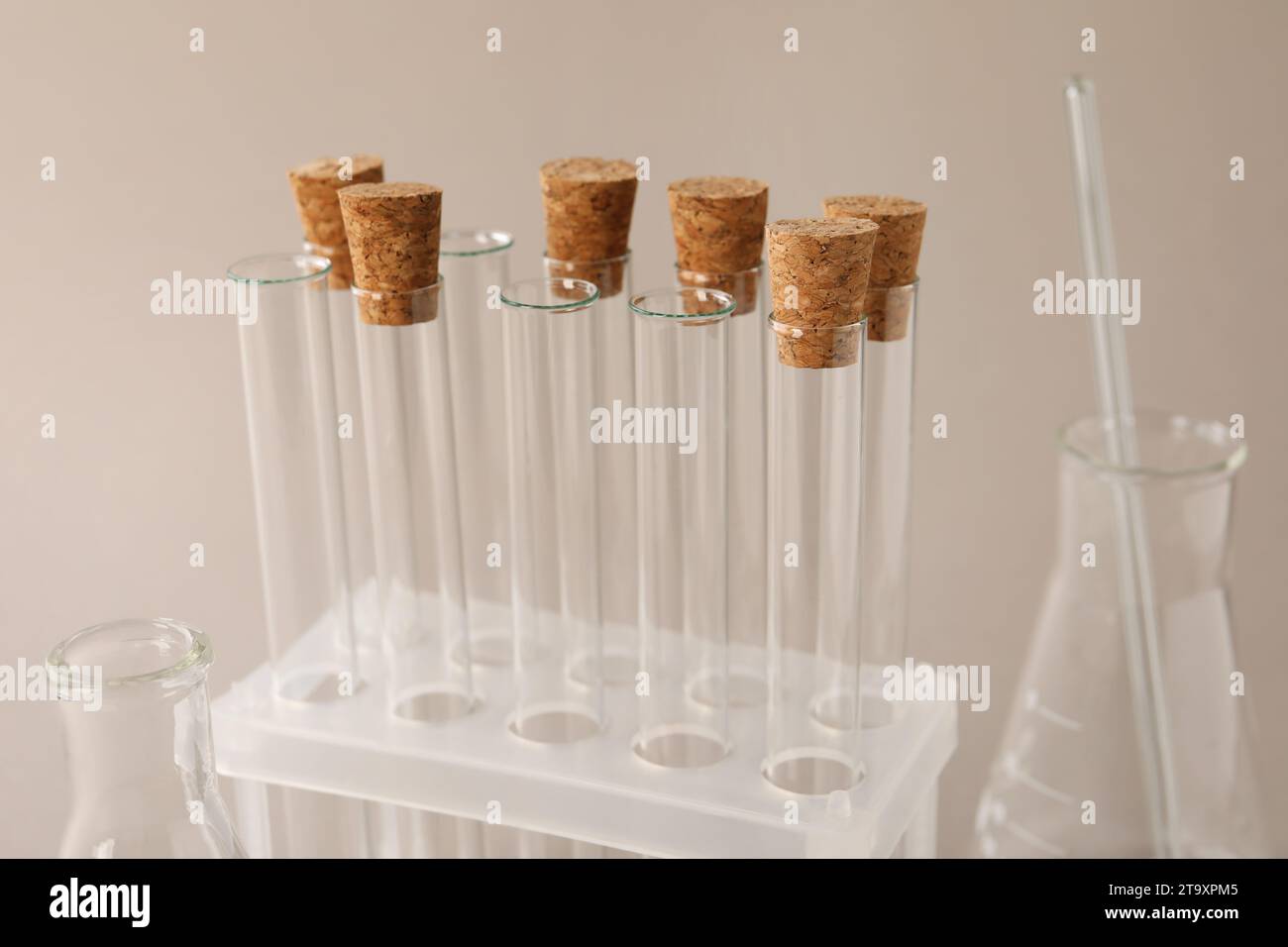 Test tubes and different laboratory flasks on beige background, closeup ...