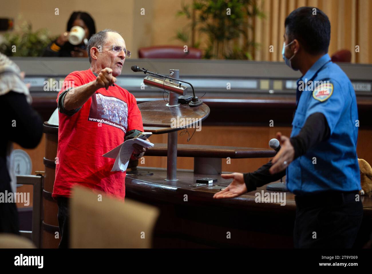 A security guard, right, ushers out a man speaking on a resolution ...
