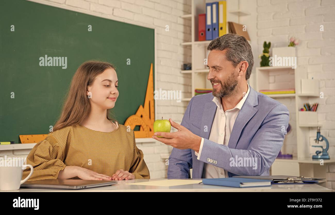 happy child in classroom with tutor sharing apple Stock Photo - Alamy