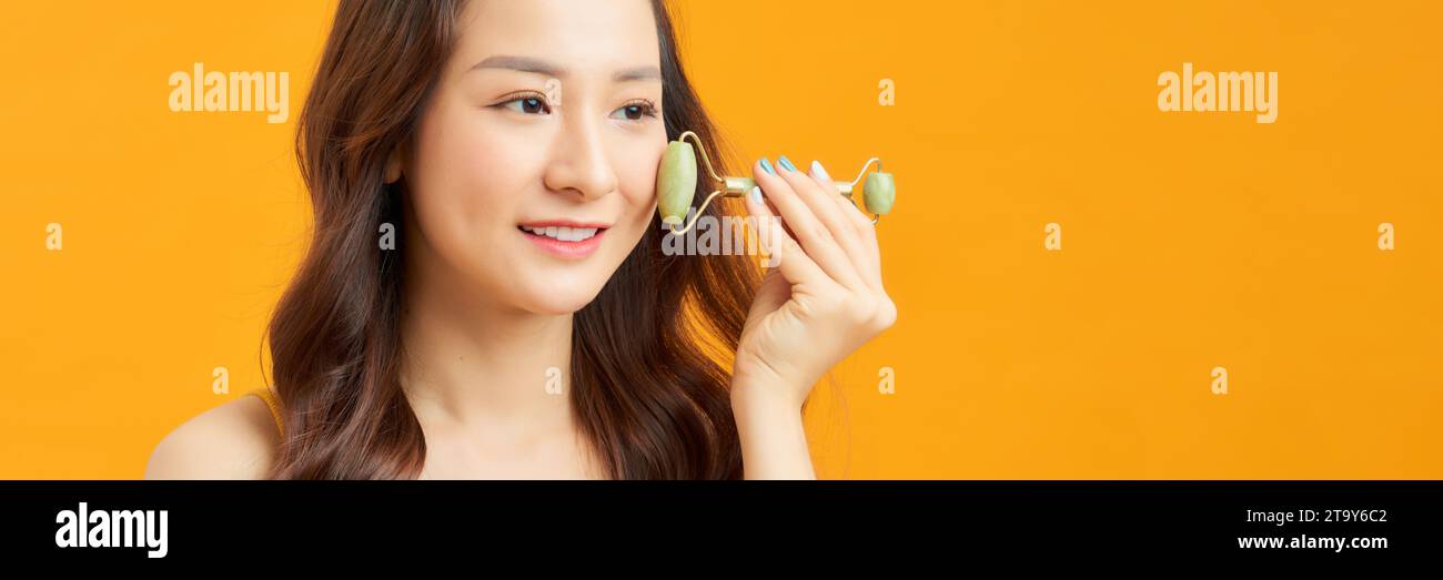 Beautiful young Asian woman using jade face roller, massager the skin ...