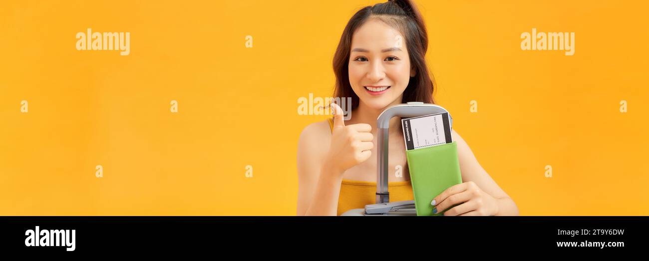 Dreamy asian tourist, smiling and thinking, holding tickets and ...