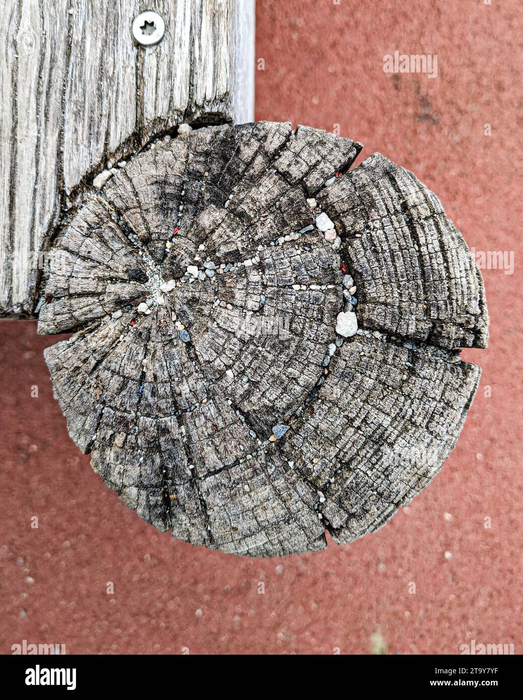 A weathered round wood post in a playground, viewed from above to show ...