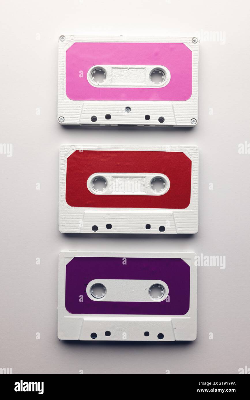 Overhead view of three colourful cassette tapes arranged on white ...