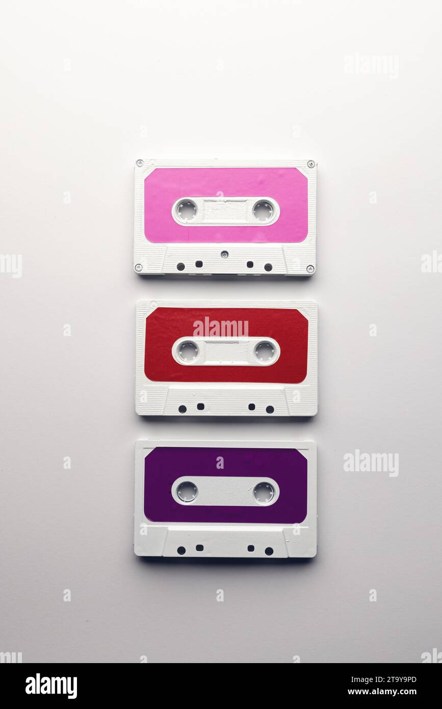 Overhead view of three colourful cassette tapes arranged on white ...