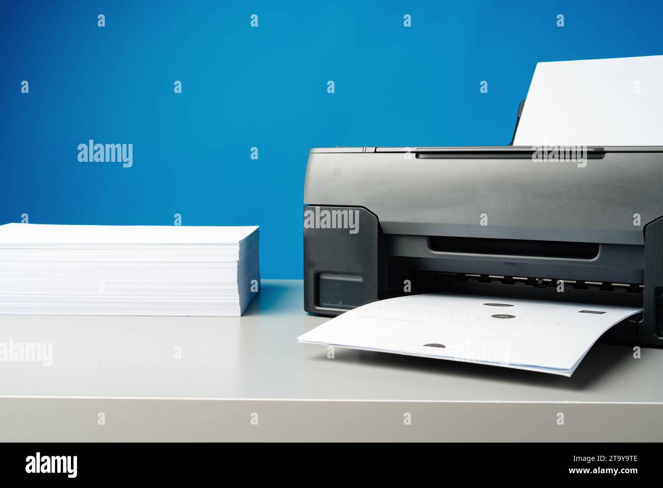 Laser printer on desk against blue background Stock Photo - Alamy