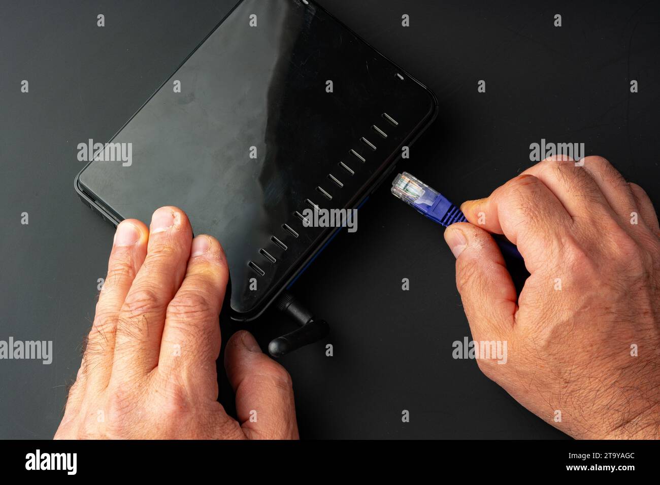 Man's hand plugging internet cable into wifi router Stock Photo - Alamy