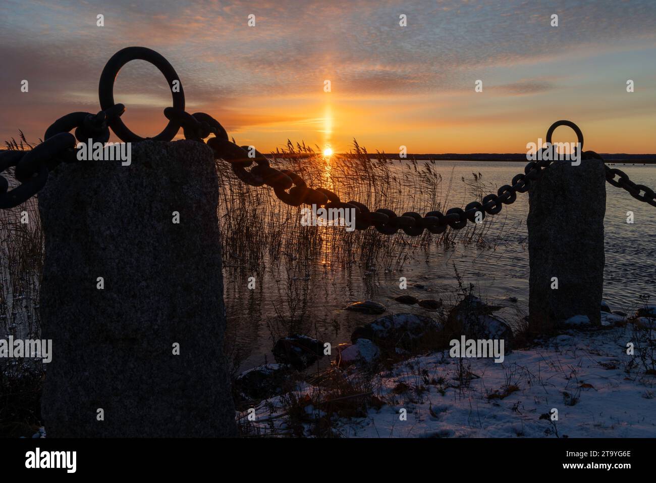 An old, rusted chain stretched across a tranquil body of water at ...