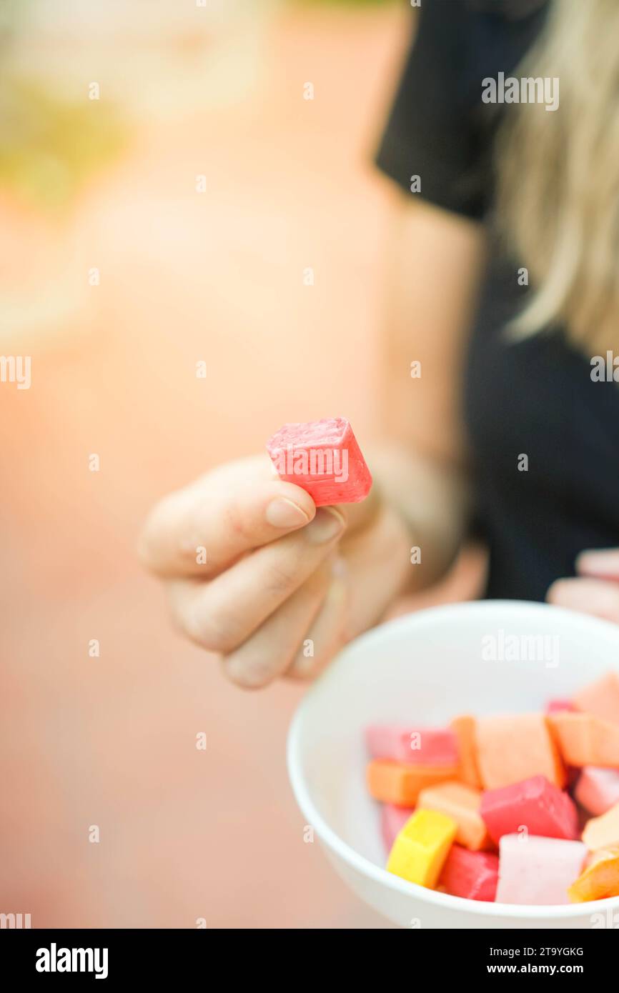 Vertical closeup view of one candy holded by unrecognizable white woman ...