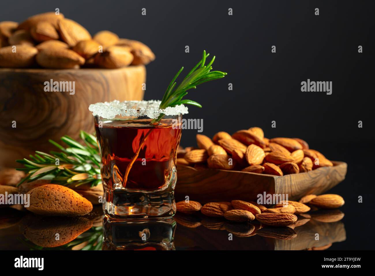 Strong alcoholic Italian liqueur Amaretto with almonds nuts on a black ...