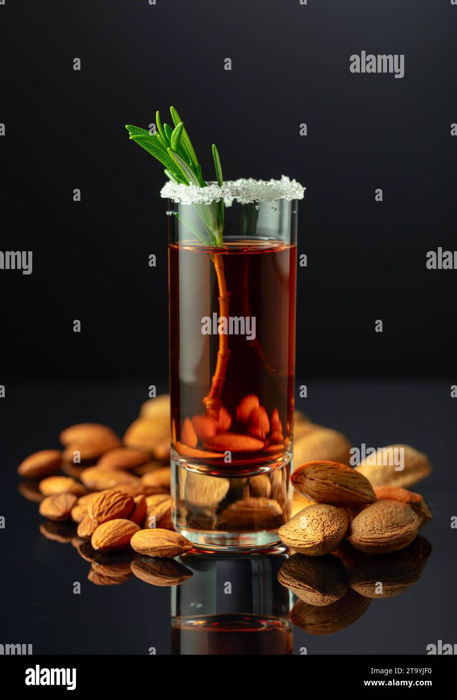 Strong alcoholic Italian liqueur Amaretto with almonds nuts on a black ...