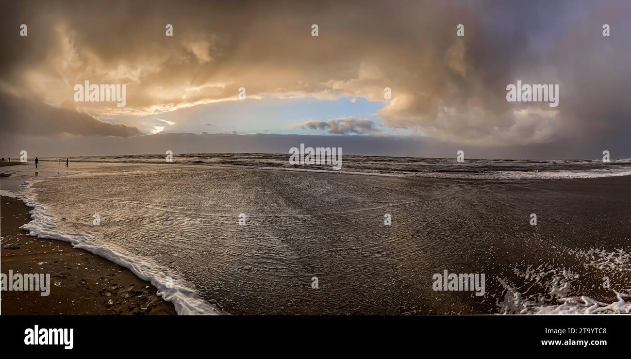 Golden sunlight, low hanging rain clouds and incoming tide during a ...