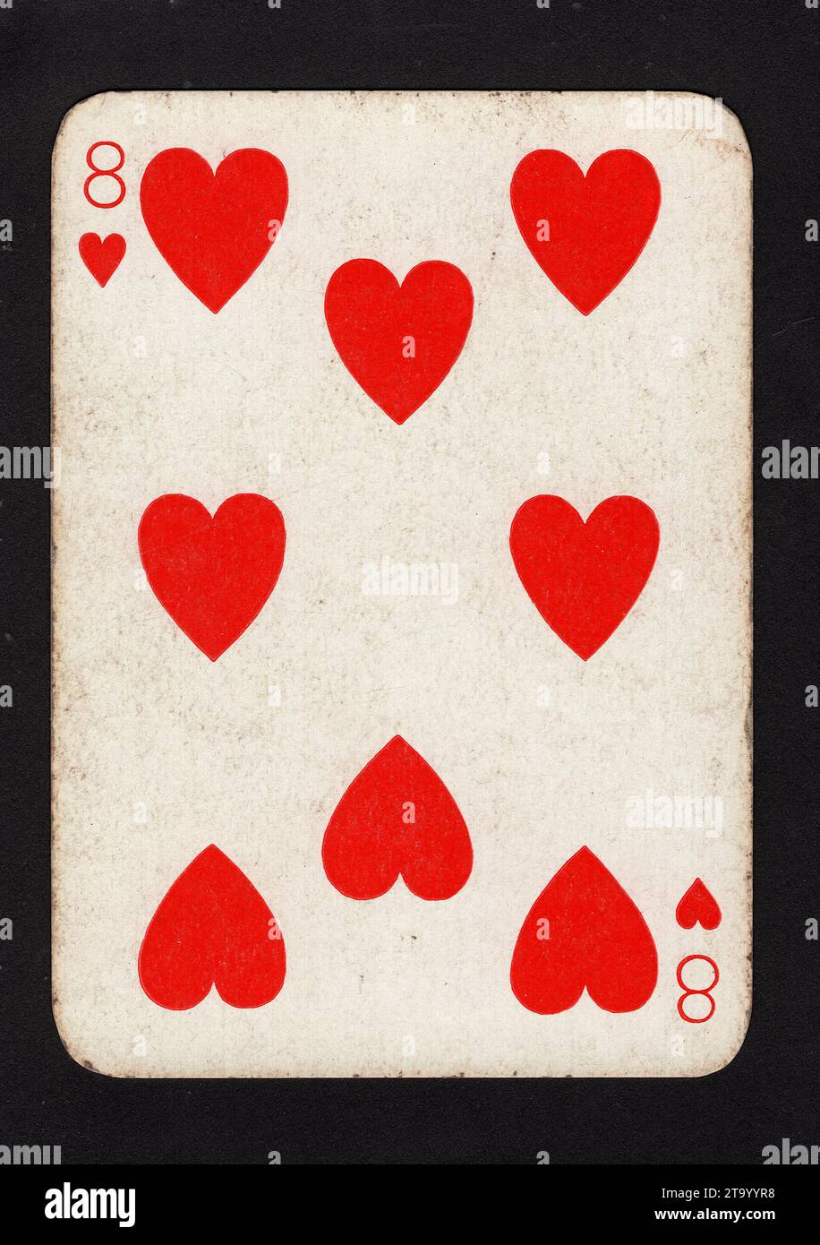 A vintage eight of hearts playing card isolated on a black background ...