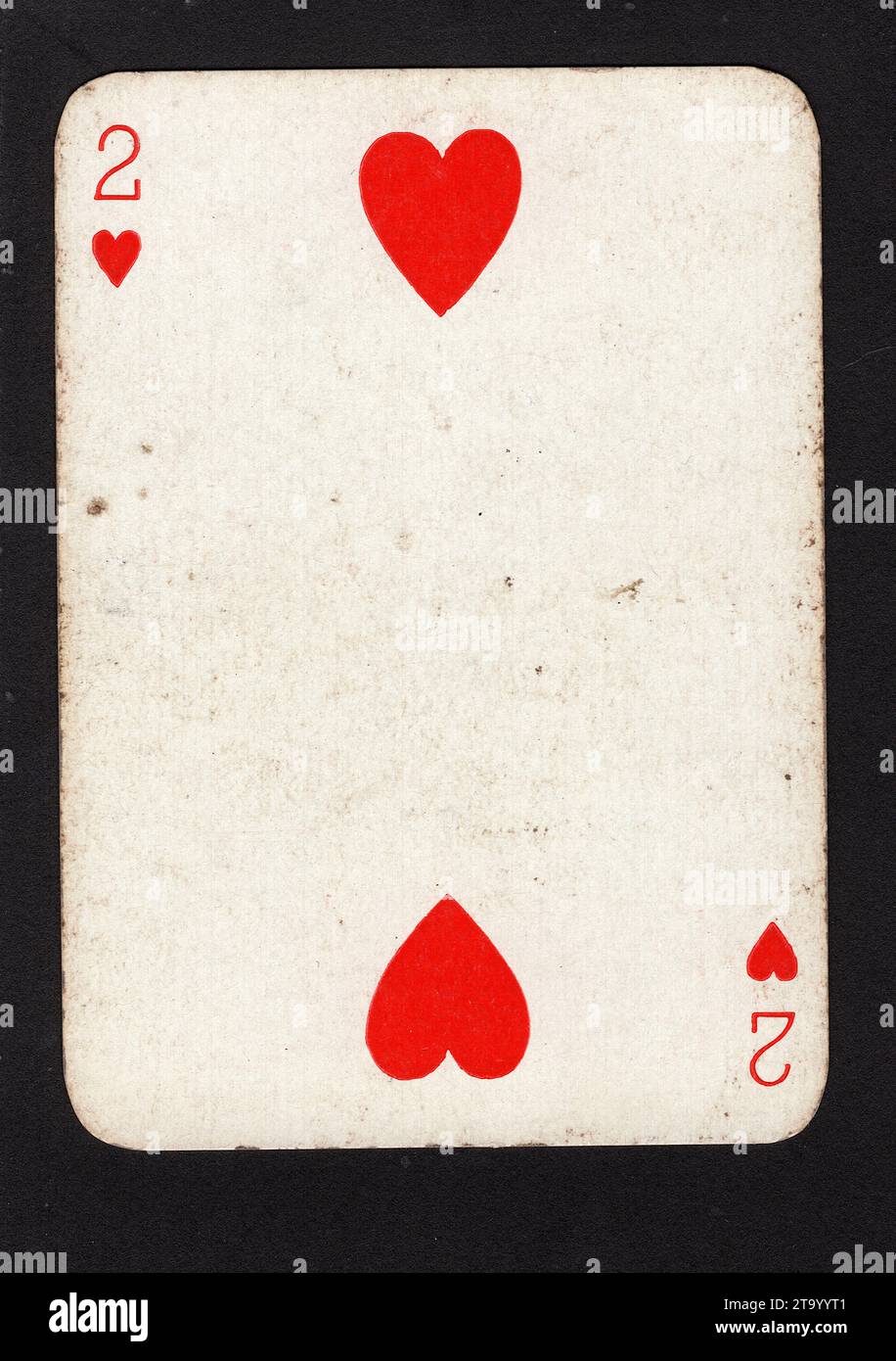 A vintage two of hearts playing card isolated on a black background ...