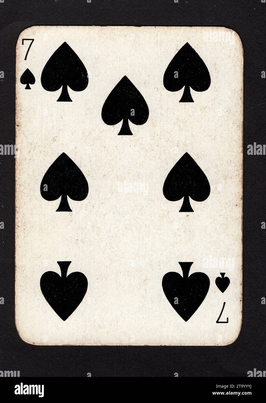A vintage seven of spades playing card isolated on a black background ...