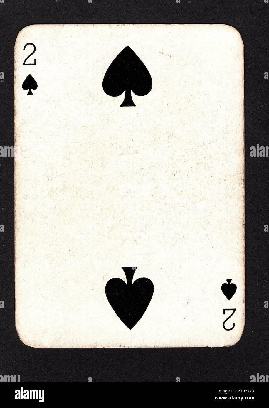 A vintage two of spades playing card isolated on a black background ...