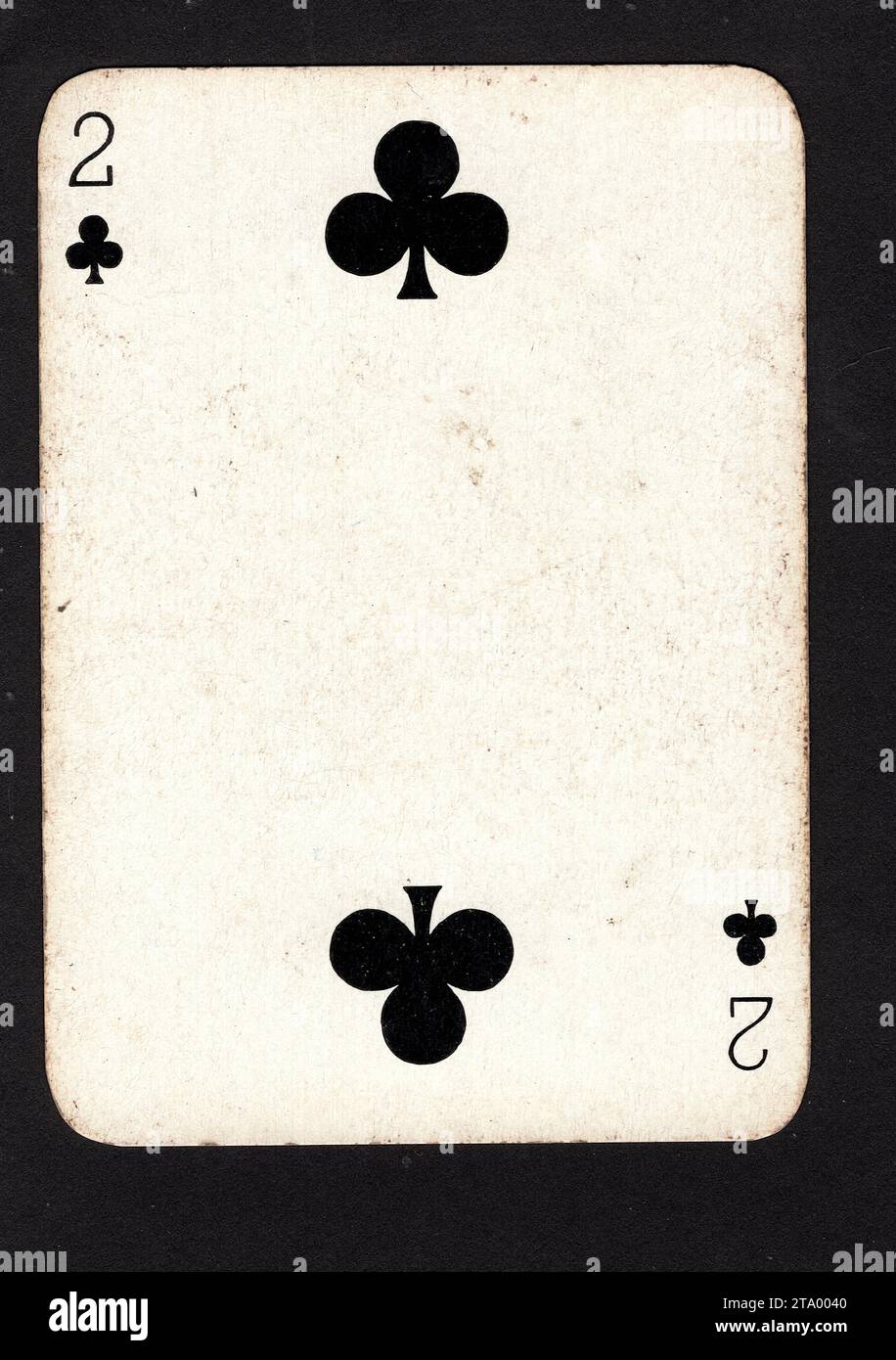A vintage two of clubs playing card isolated on a black background ...