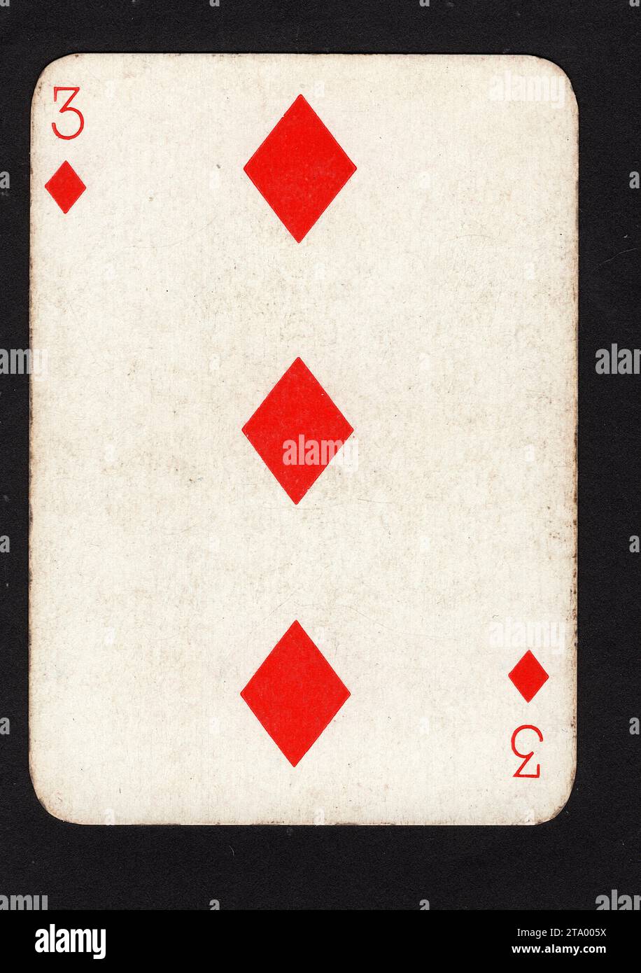 A vintage three of diamonds playing card isolated on a black background ...