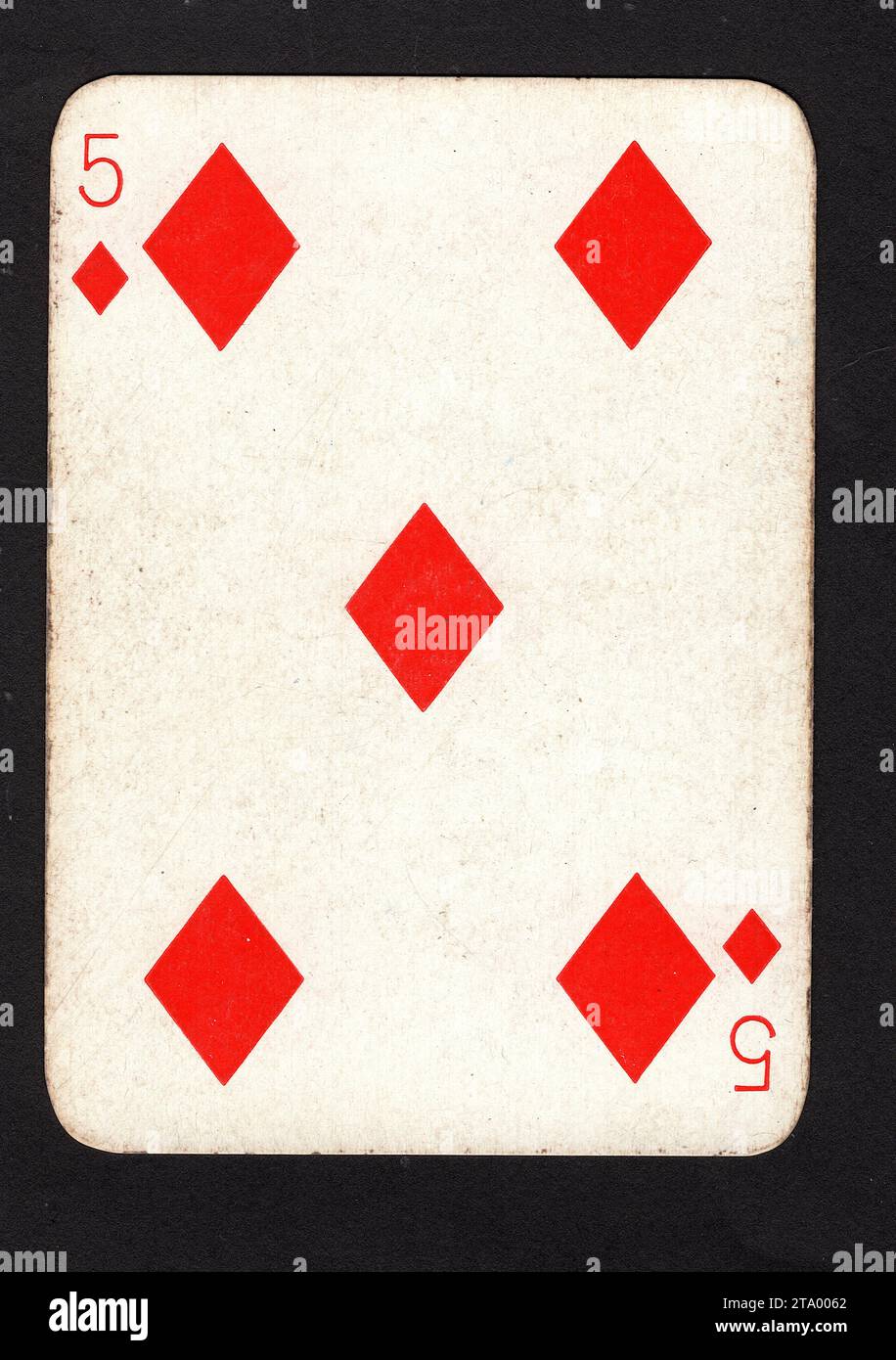 A vintage five of diamonds playing card isolated on a black background ...