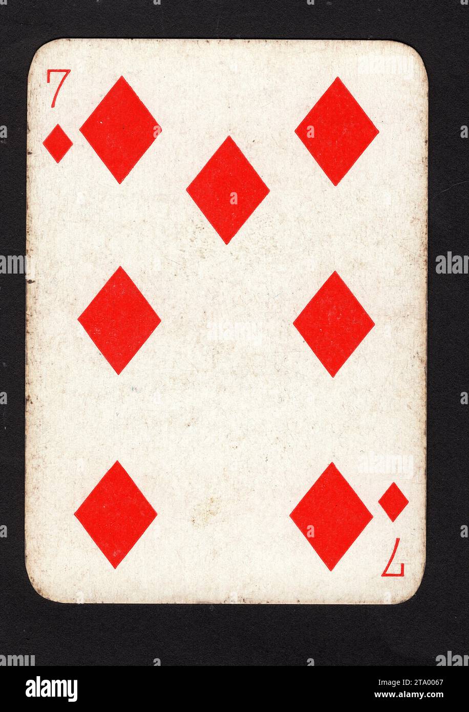 A vintage seven of diamonds playing card isolated on a black background ...