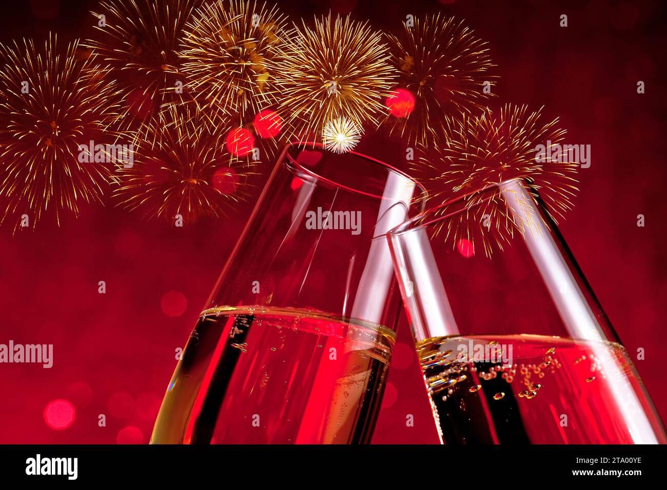 champagne flutes with golden bubbles make cheers on red light bokeh and ...