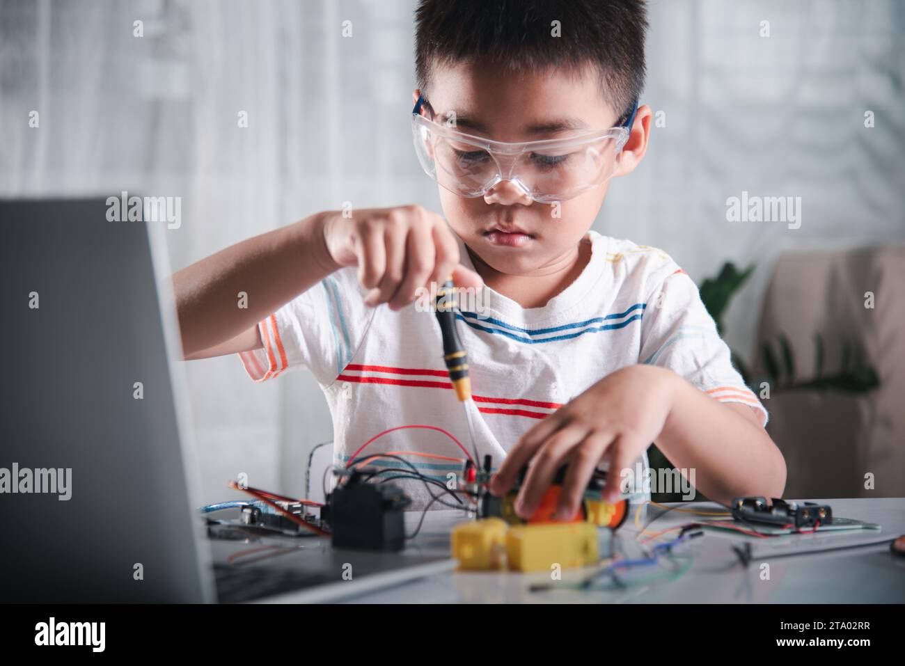 Asian kid boy assembling the Arduino robot car homework project at home ...