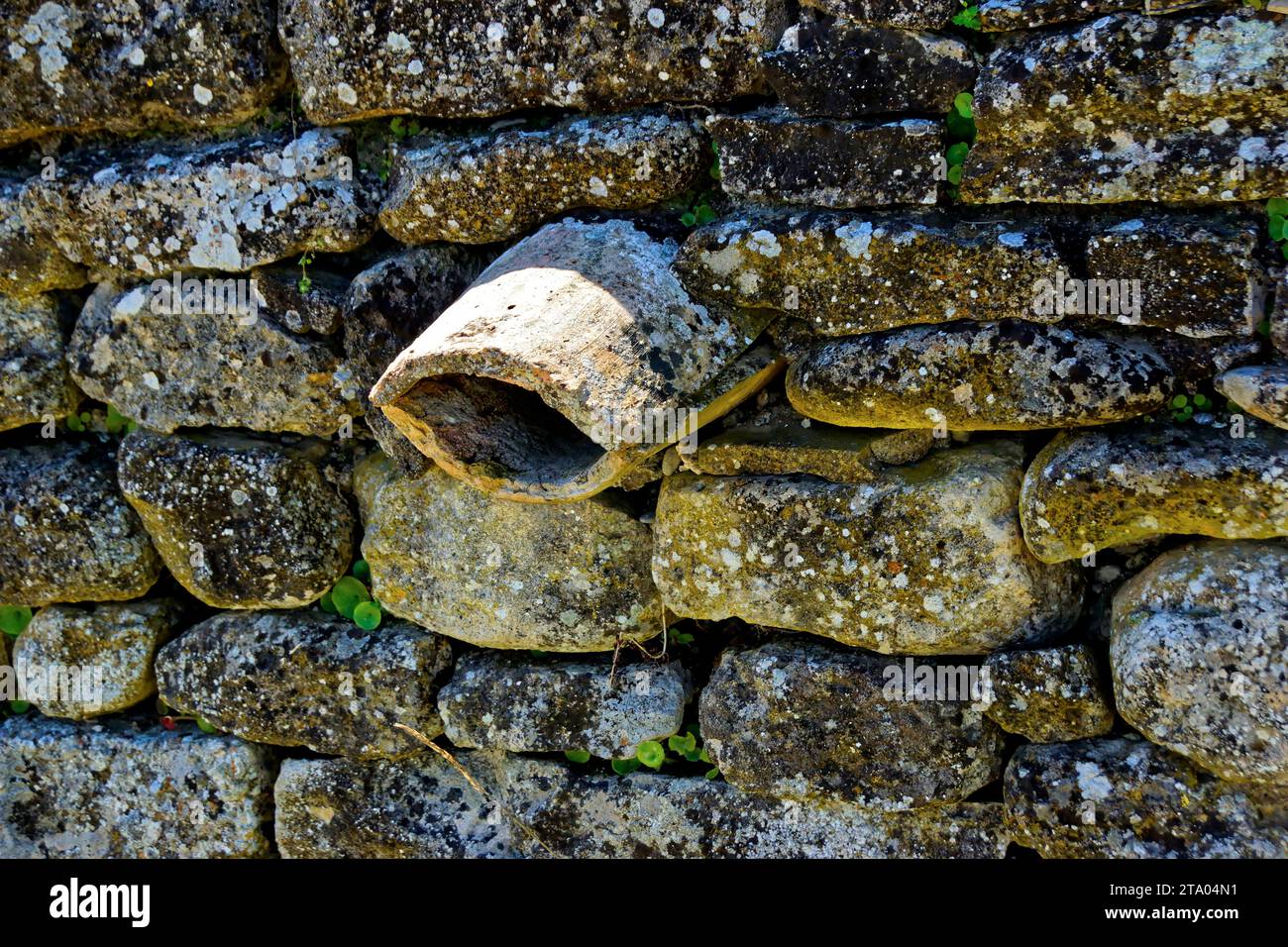 un mur en pierre sèche avec une barbacane faite de tuile en terre cuite ...