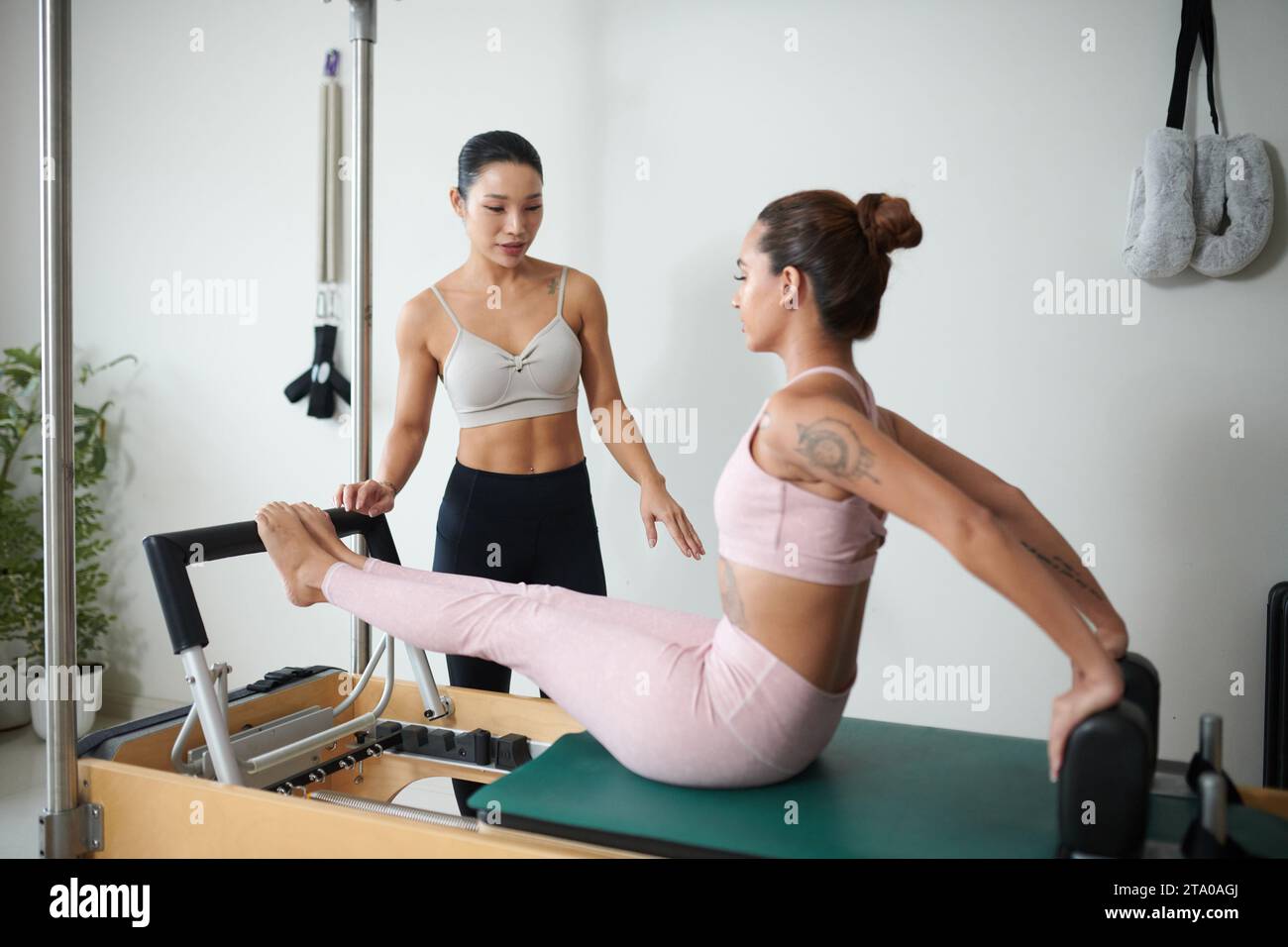 Personal trainer explaining client how to do exercise in special machine to strengthen core ...