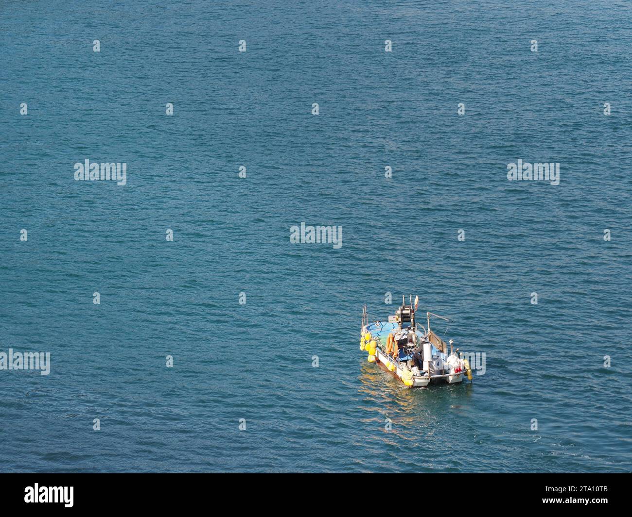 A yellow, small-sized boat is seen in a peaceful lake, bobbing gently ...
