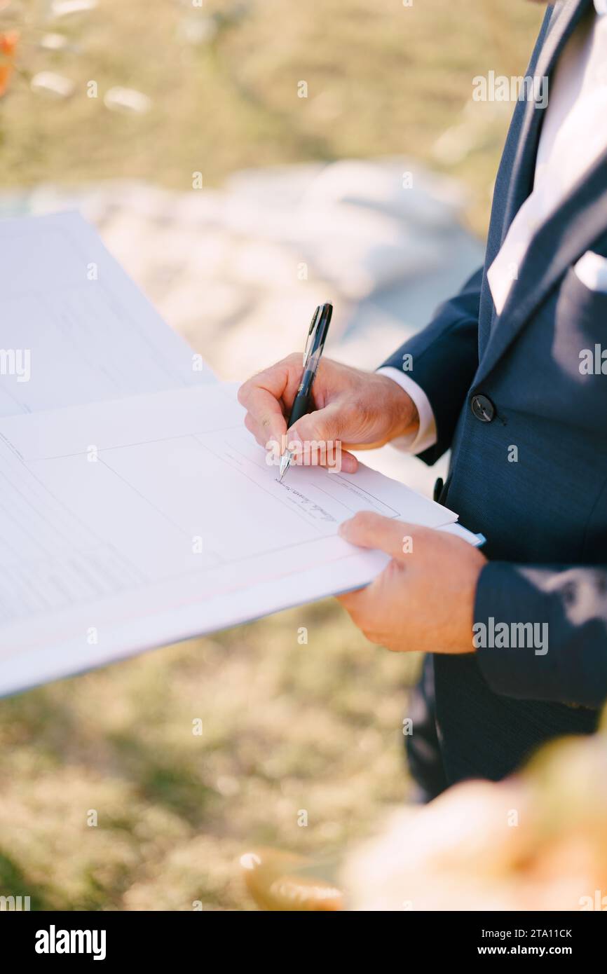 Groom puts signature in registration hi-res stock photography and ...