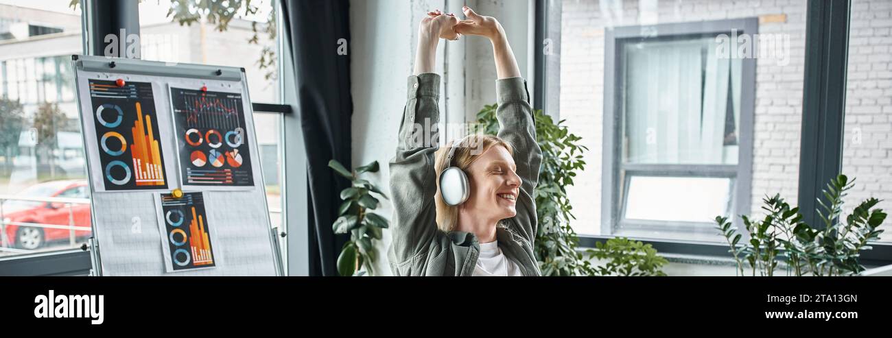 young non binary person in casual attire sitting with headphones at ...
