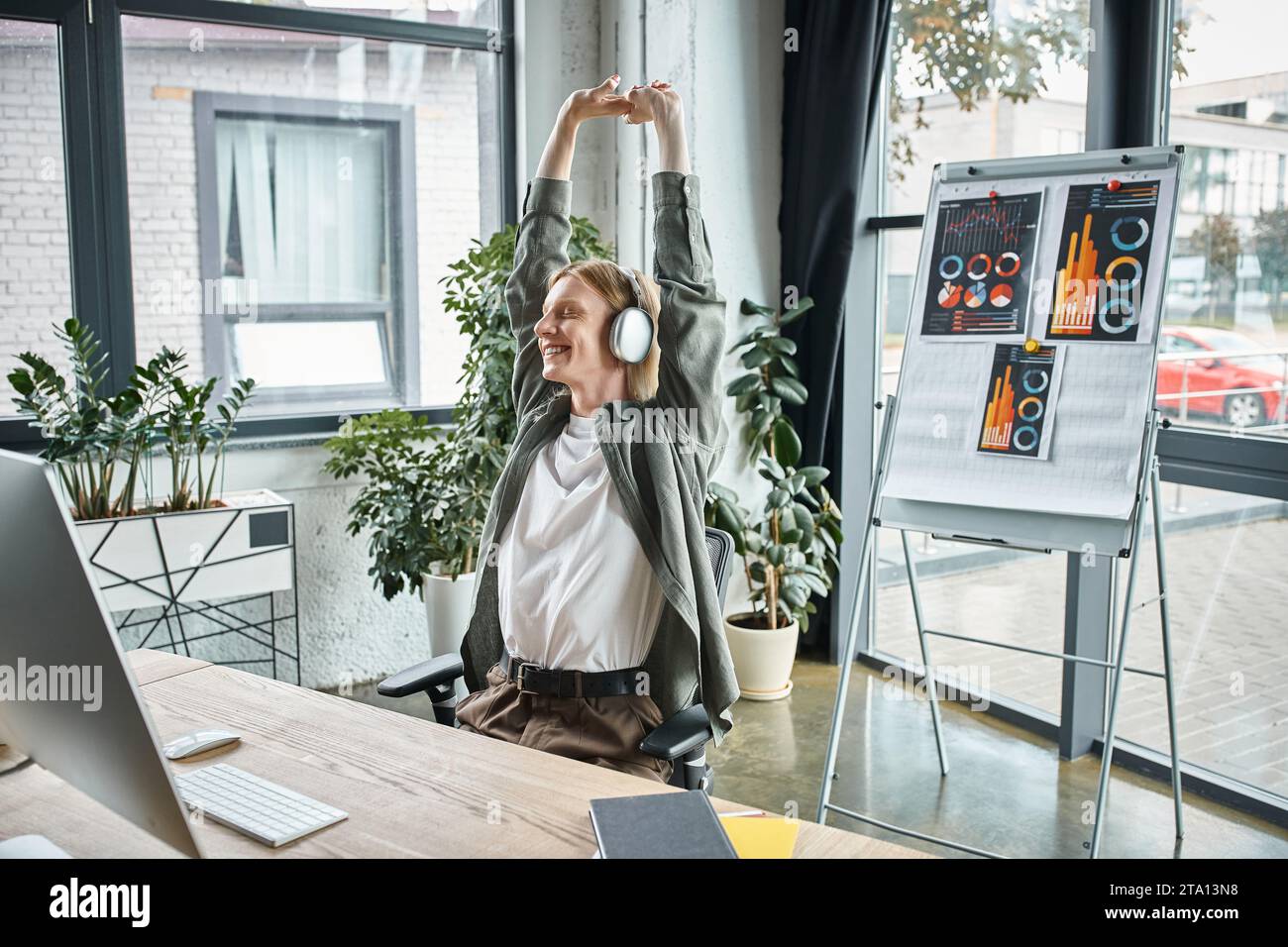 young non binary person in business casual attire sitting in headphones ...