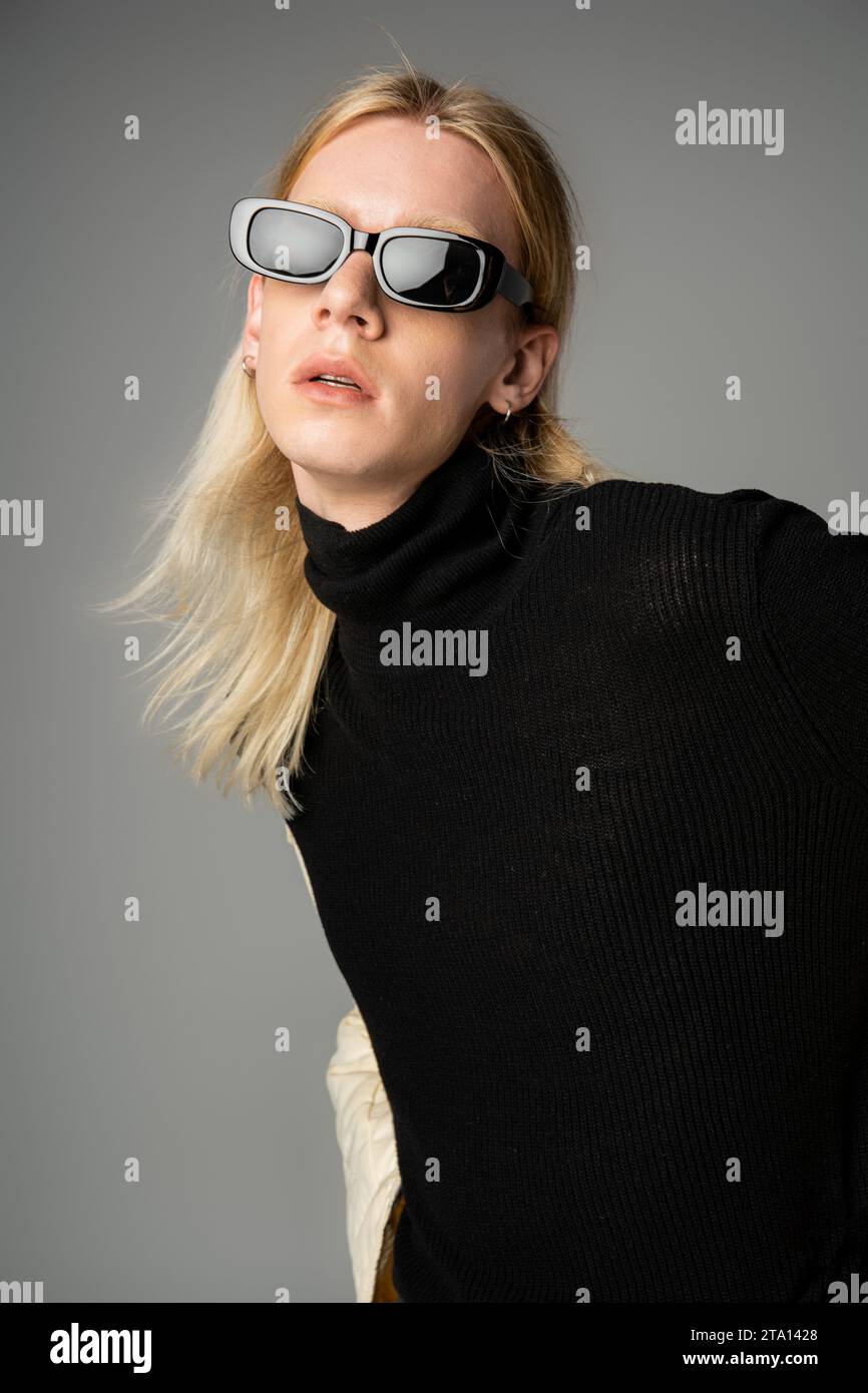 young non binary person in stylish sunglasses with long hair posing on ...
