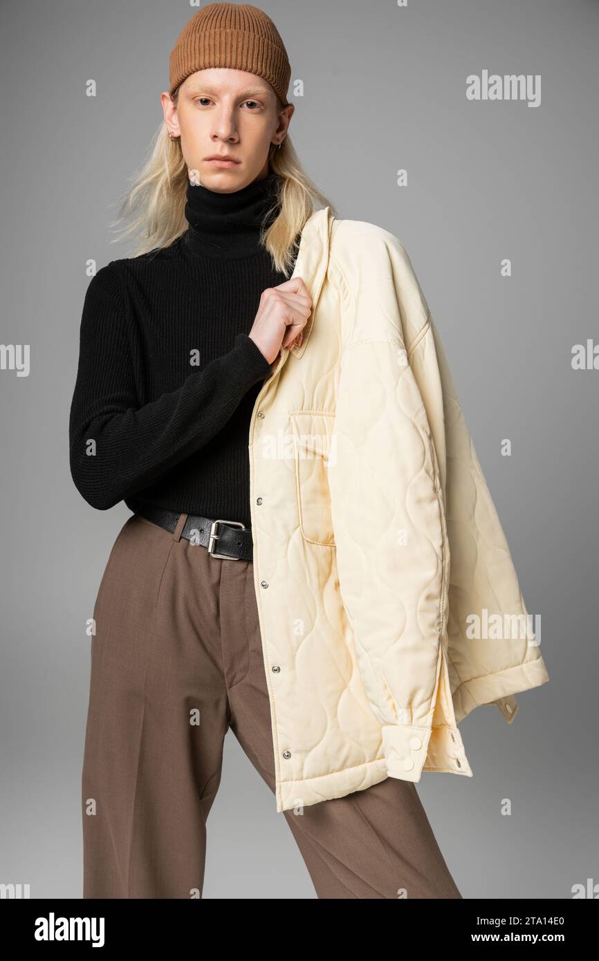 good looking non binary model posing with stylish winter jacket on ...