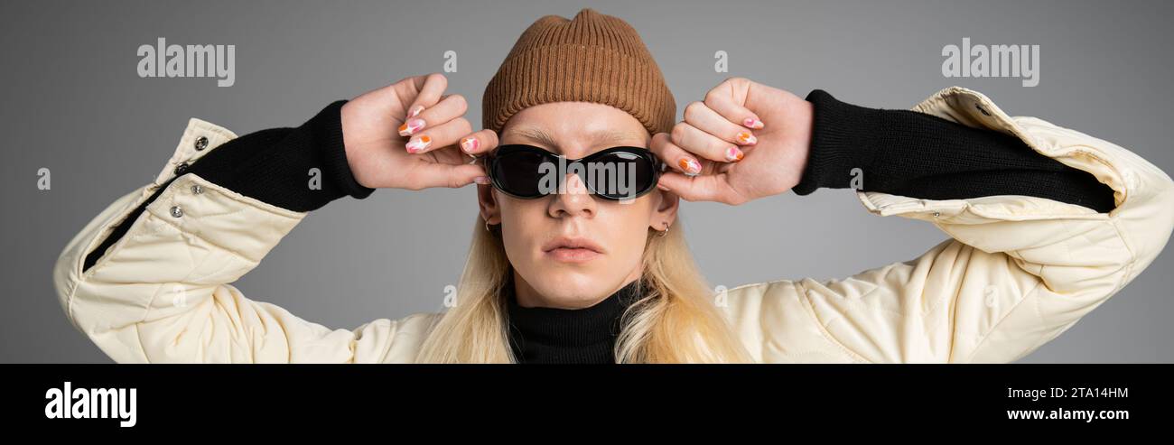appealing stylish non binary model in warm attire touching sunglasses ...
