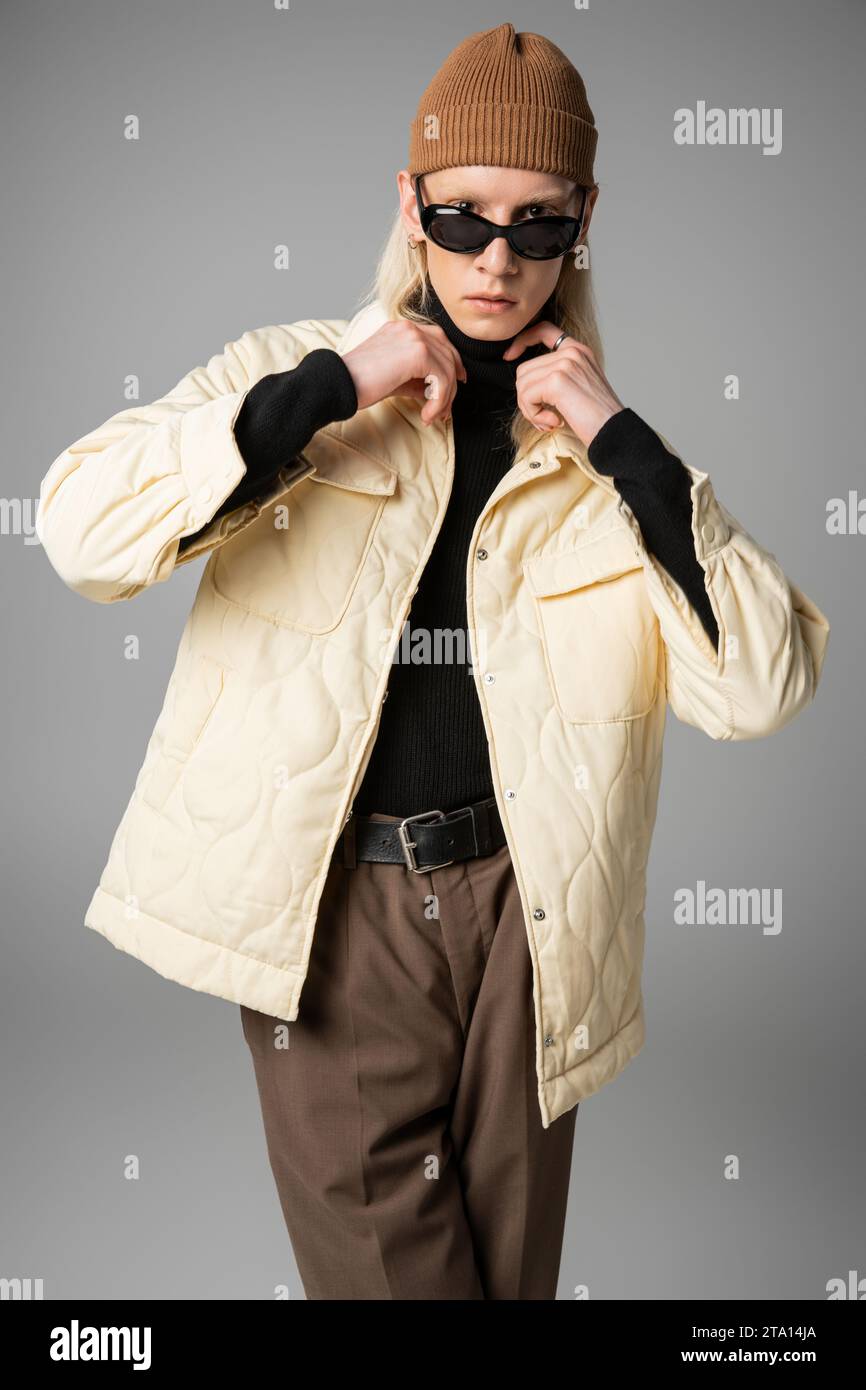 young non binary model in winter jacket touching collar of black ...