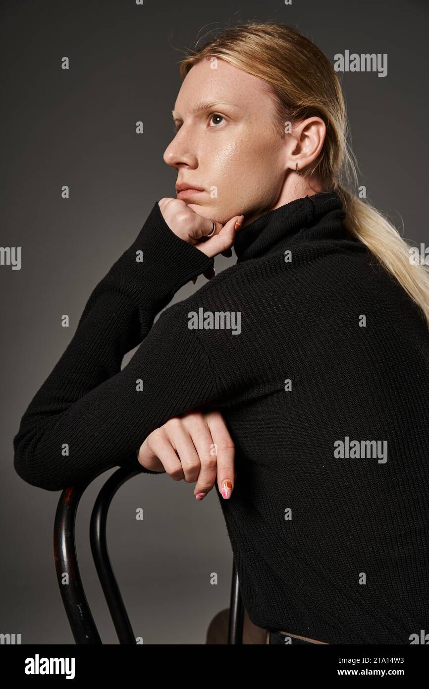 young non binary model in stylish attire posing in profile with hand ...