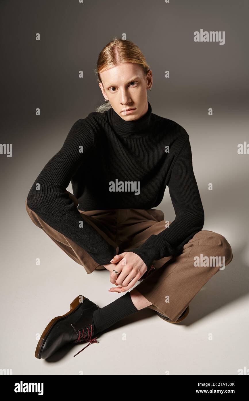 appealing non binary person with red hair and ponytail sitting on floor ...